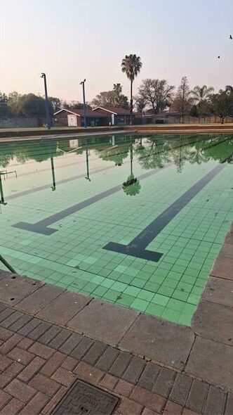 Vrywilligers laat waai met besems om swembadvloer veilig te kry vir ...